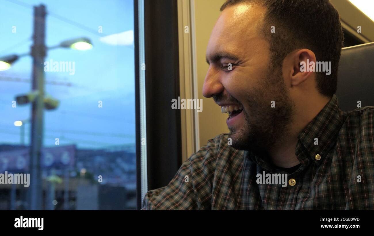 Hard laughing young man in a train Stock Photo - Alamy