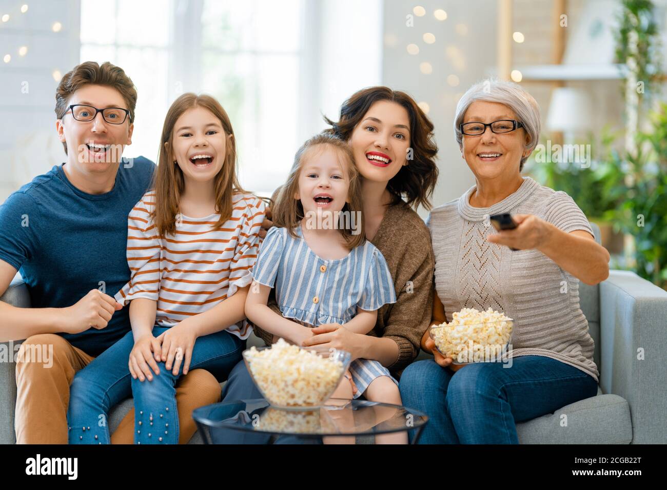 Happy family watching projector, TV, movies with popcorn in the evening ...