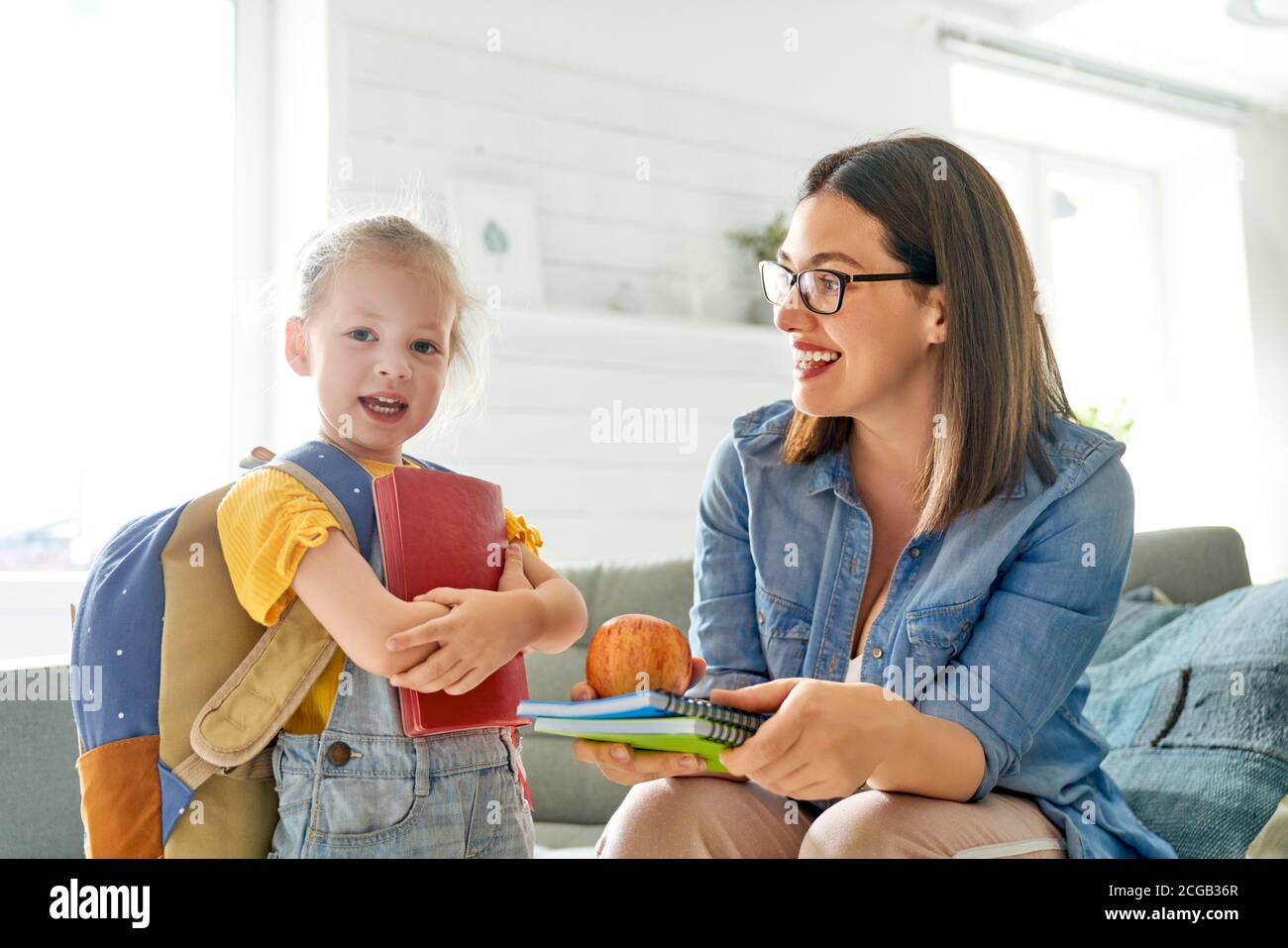 Parent and pupil of preschool. Woman and girl with backpack behind back ...