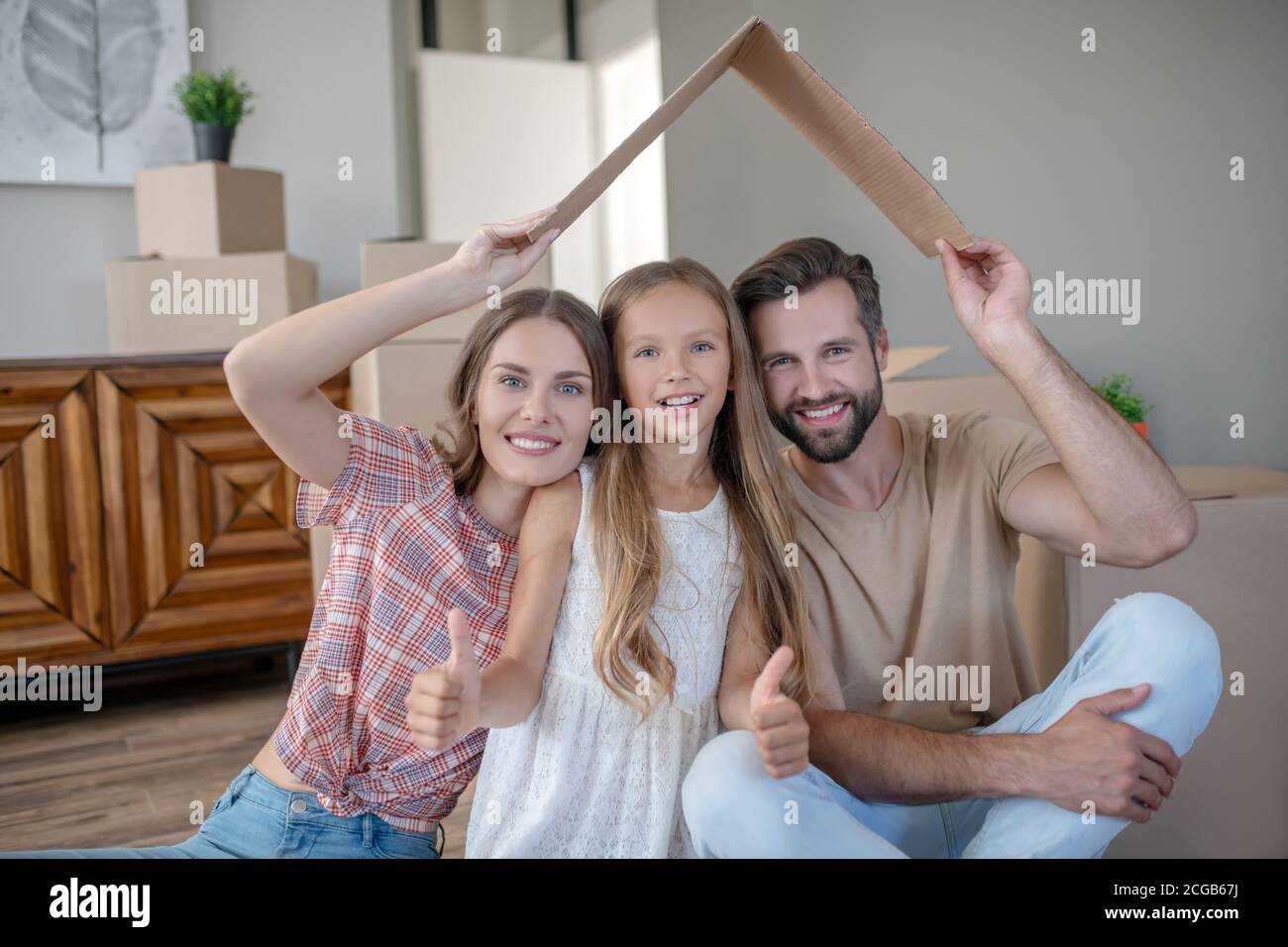 Family sitting under paper roof and feeling happy Stock Photo - Alamy