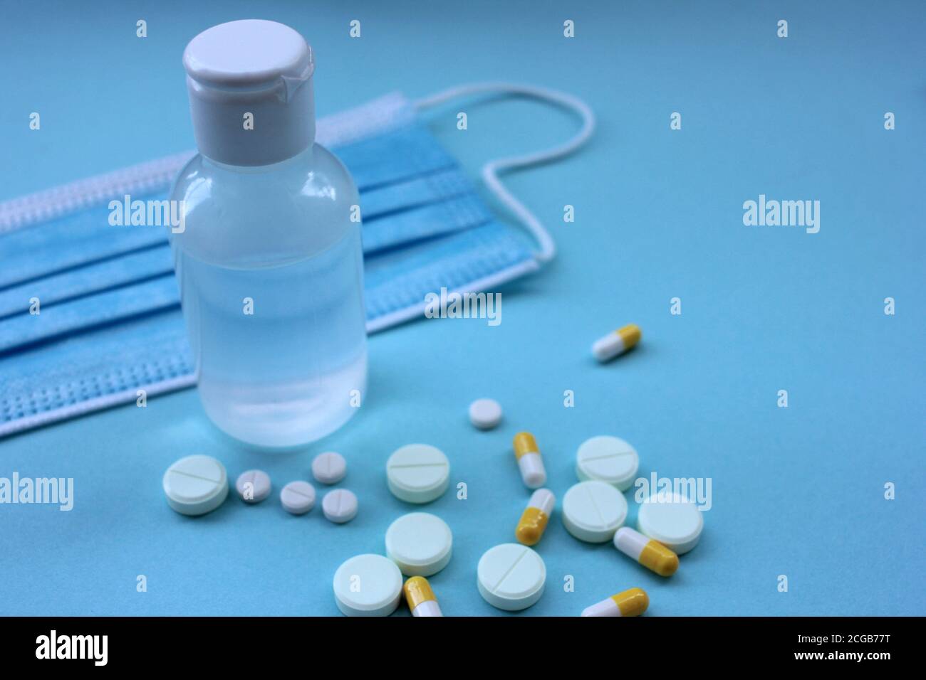 White pills, yellow capsules, hand sanitizer bottle, and coronavirus ...
