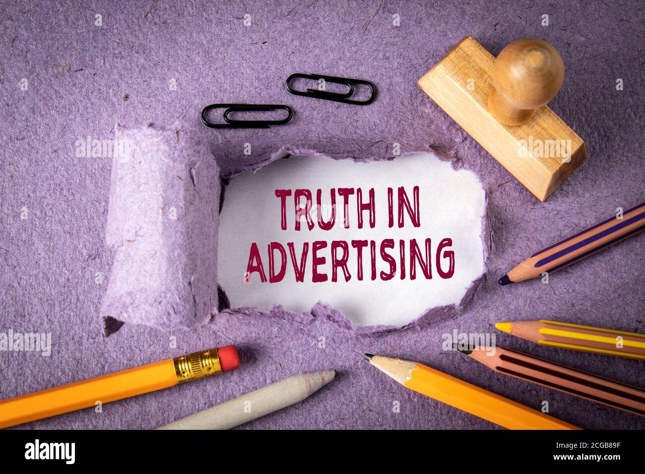 TRUTH IN ADVERTISING. Purple paper, wooden stamp and pencils. Text ...