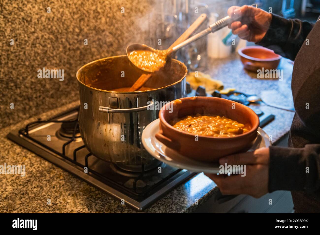 woman serving locro, typical Argentine food on handmade ceramic plates ...