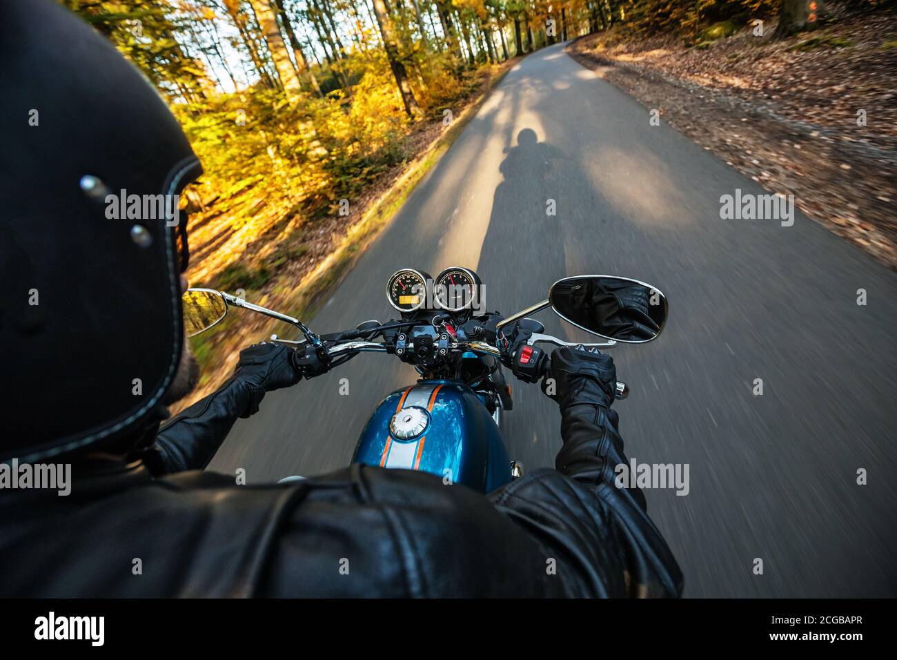 View from motorcycle driver perspective riding in forest during sunrise ...
