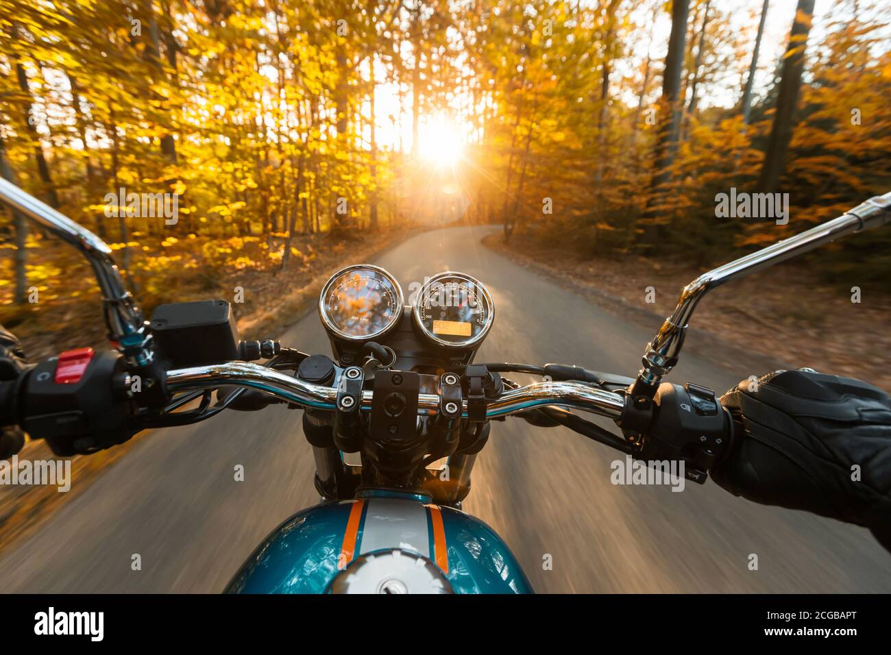 View from motorcycle driver perspective riding in forest during sunrise ...