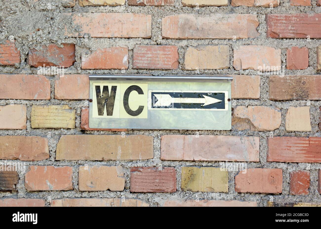 Toilet sign on an old brick wall, go right Stock Photo - Alamy
