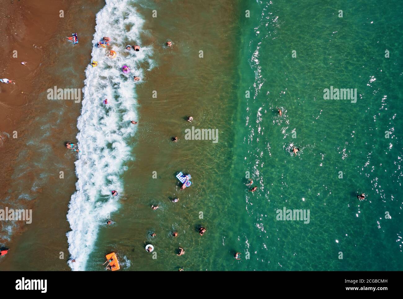 Aerial view of sandy beach with tourists swimming in beautiful clear ...
