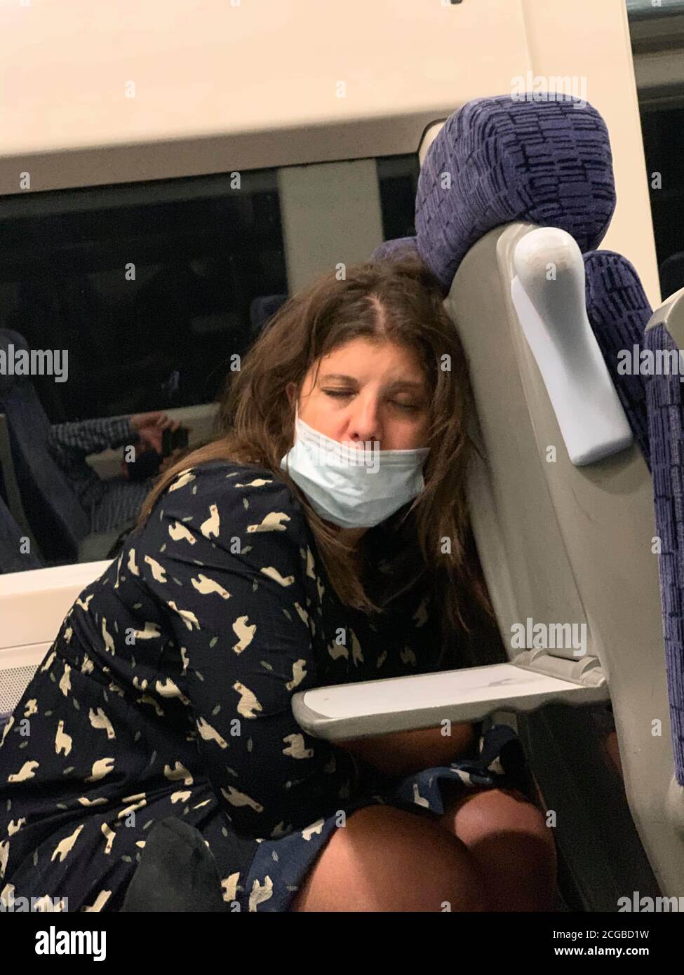 Young woman asleep on a train wearing face mask Stock Photo - Alamy