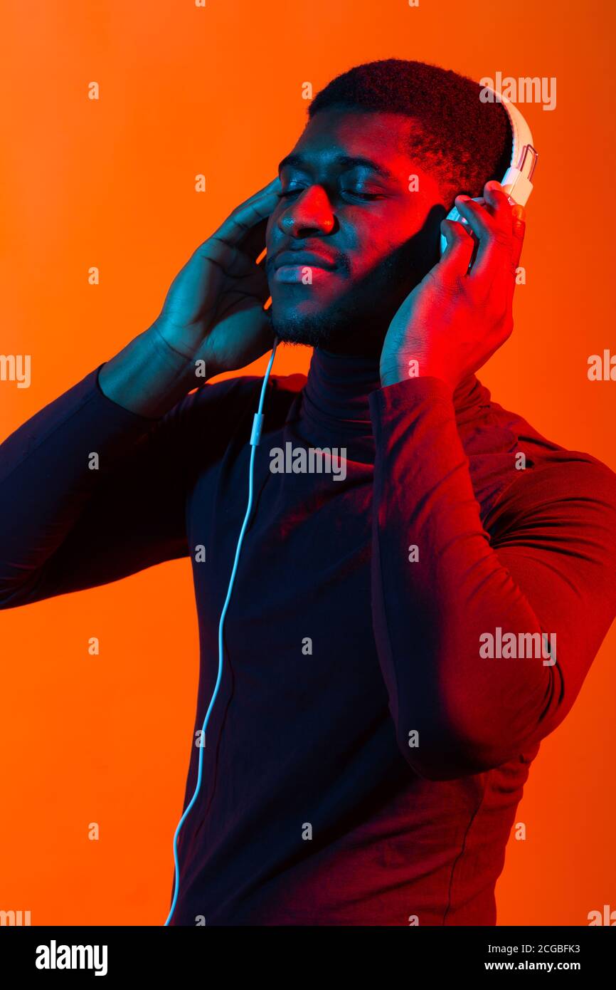 Neon portrait of young african man listening music with earphones Stock Photo - Alamy