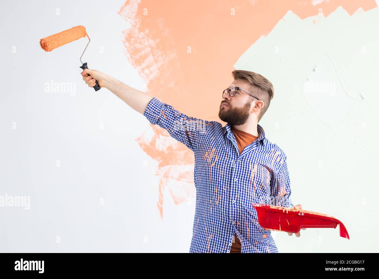 Male painting the wall with paint roller. Portrait of a funny guy ...