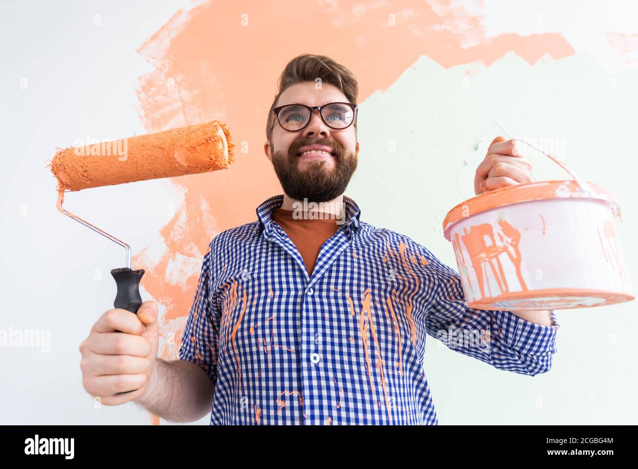 Male painting the wall with paint roller. Portrait of a funny guy ...