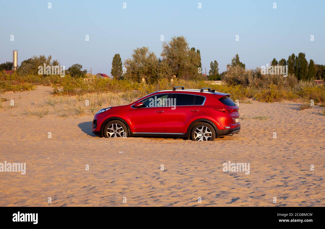 The red car skidded in the sand on the beach. The wheels are stuck in ...