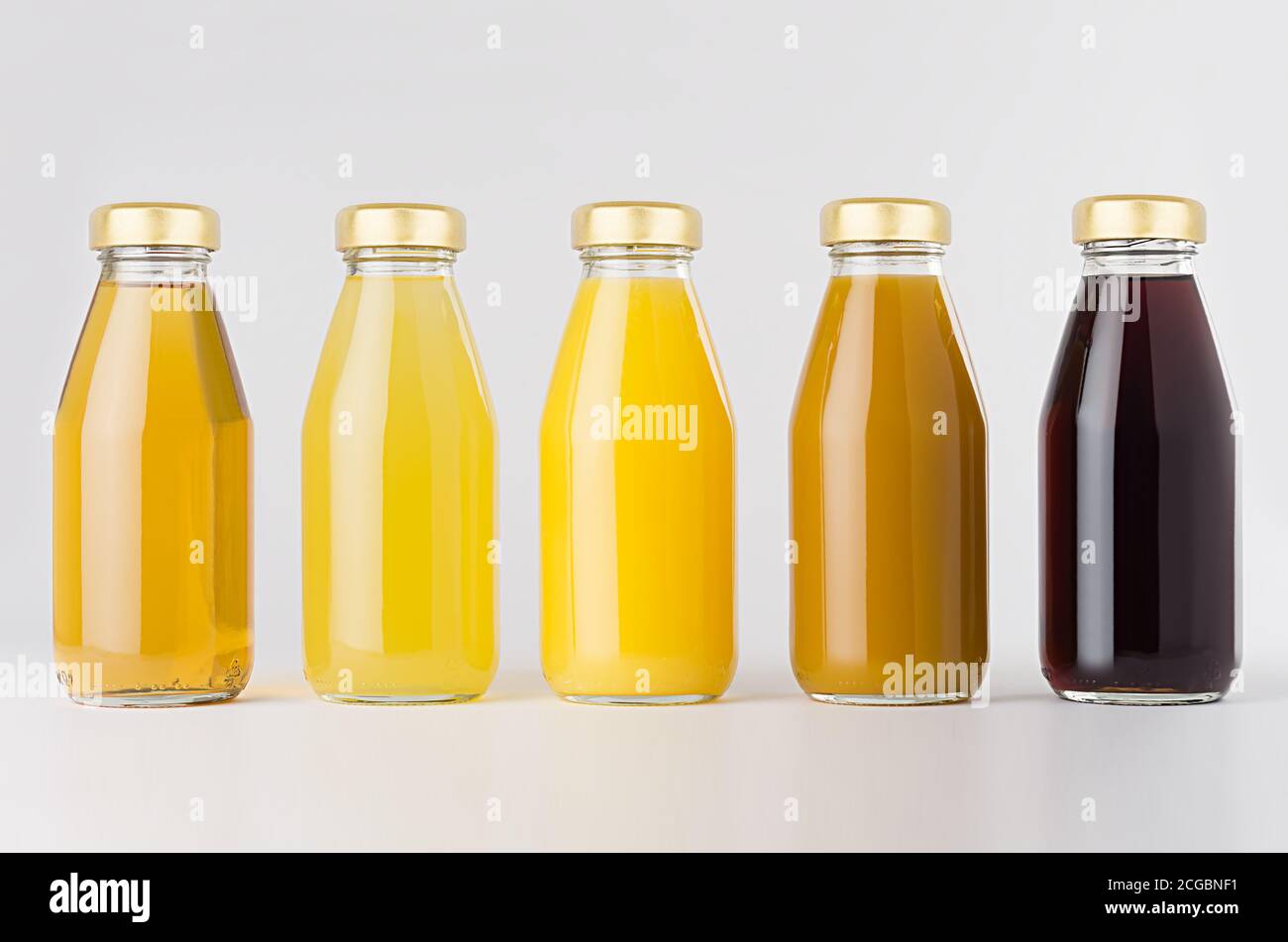 Yellow, orange, red fruit juices large collection in glass bottles with ...