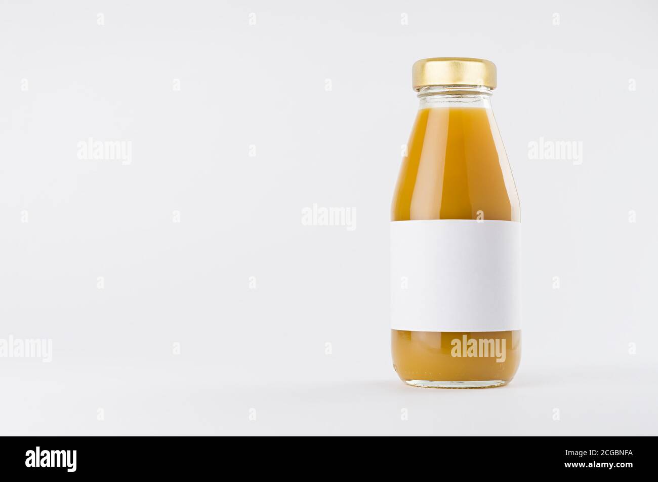 Orange mango juice in glass bottle with gold cap and white blank label ...