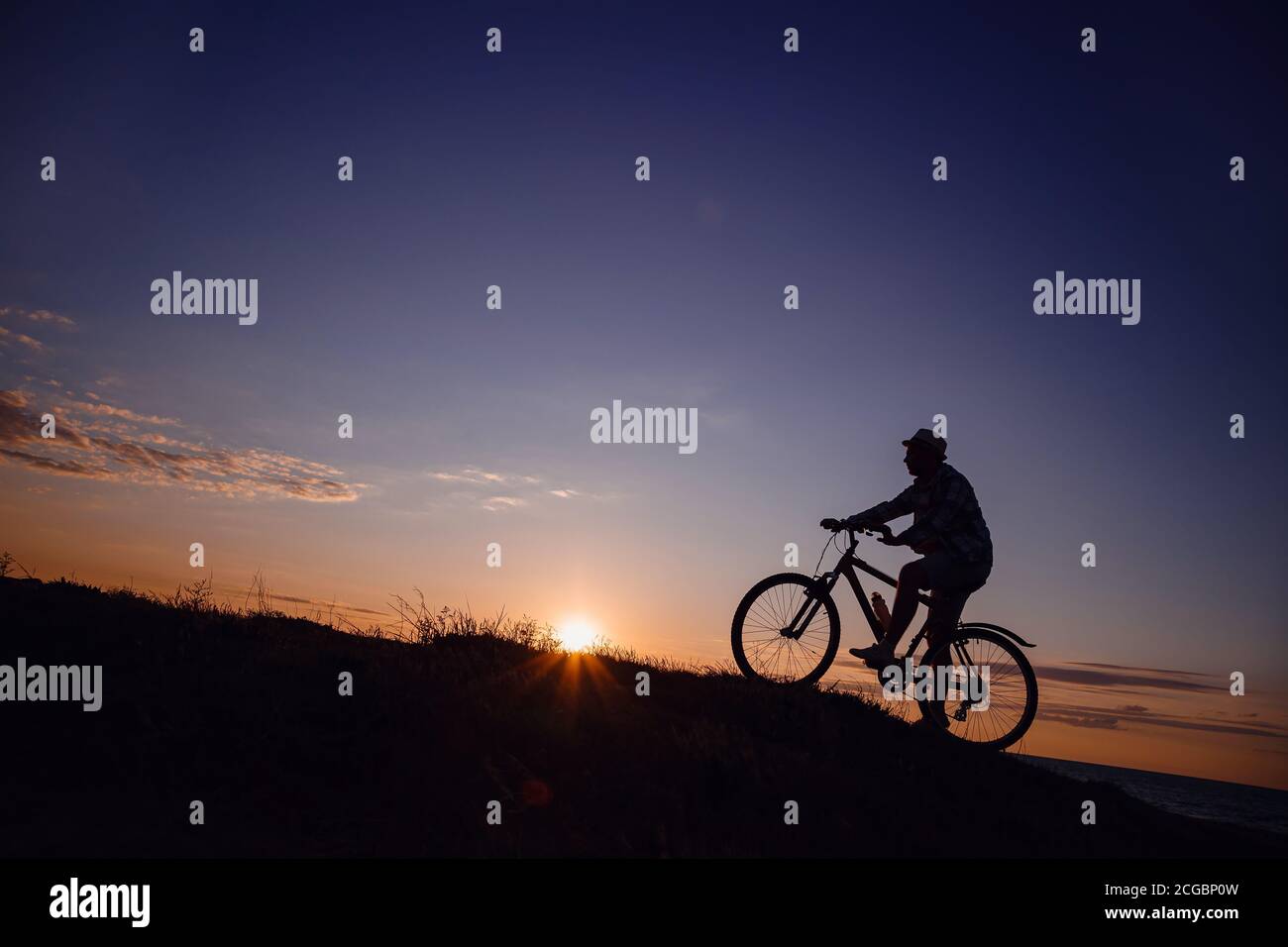 silhouette of a hipster man on a bicycle on sunset background. Idea and ...