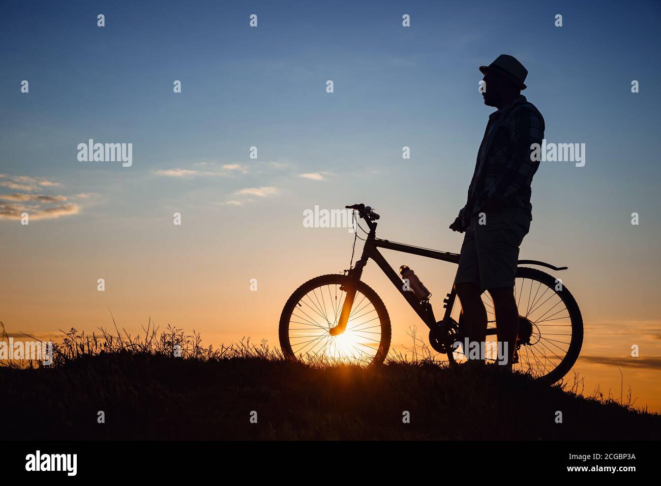 silhouette of a hipster man on a bicycle on sunset background. Idea and ...