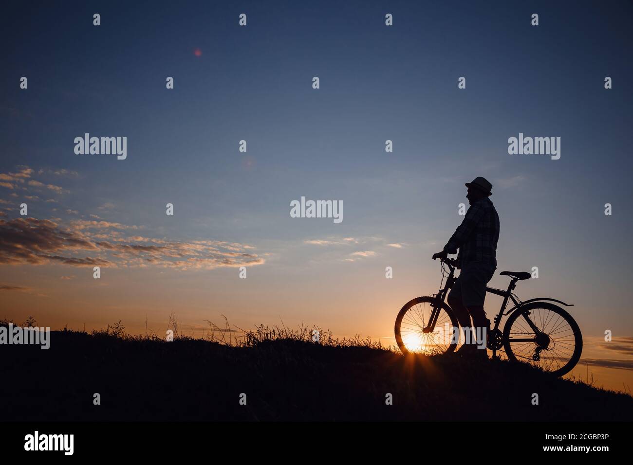 silhouette of a hipster man on a bicycle on sunset background. Idea and ...