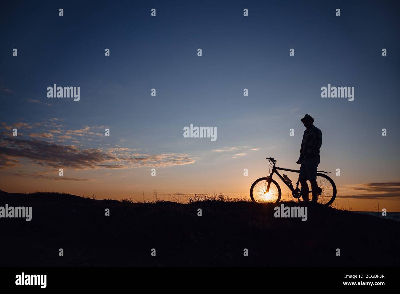 silhouette of a hipster man on a bicycle on sunset background. Idea and ...