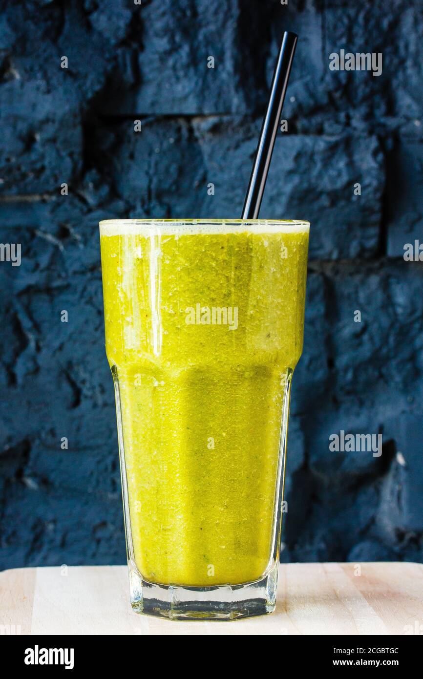 Yellow smoothie (orange, mandarin) in a large glass cup against a dark ...