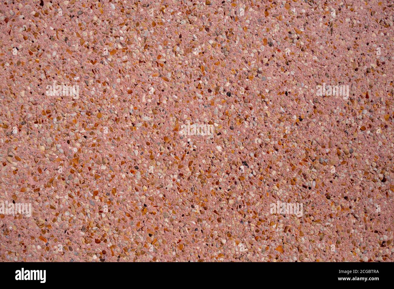 decorative wall with small stones in pink cement Stock Photo - Alamy