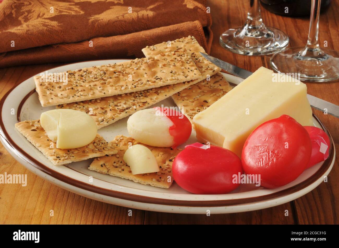 A wedge of asigo cheese with assorted cheeses in a red wax wrapper ...