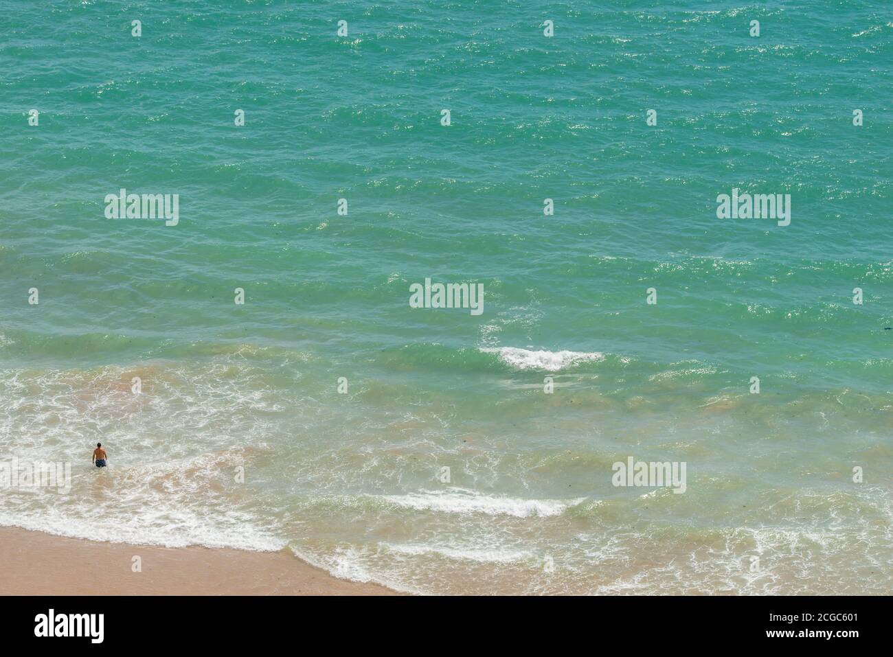 Lone bather entering the Atlantic Ocean water at Recife beach, Brazil ...