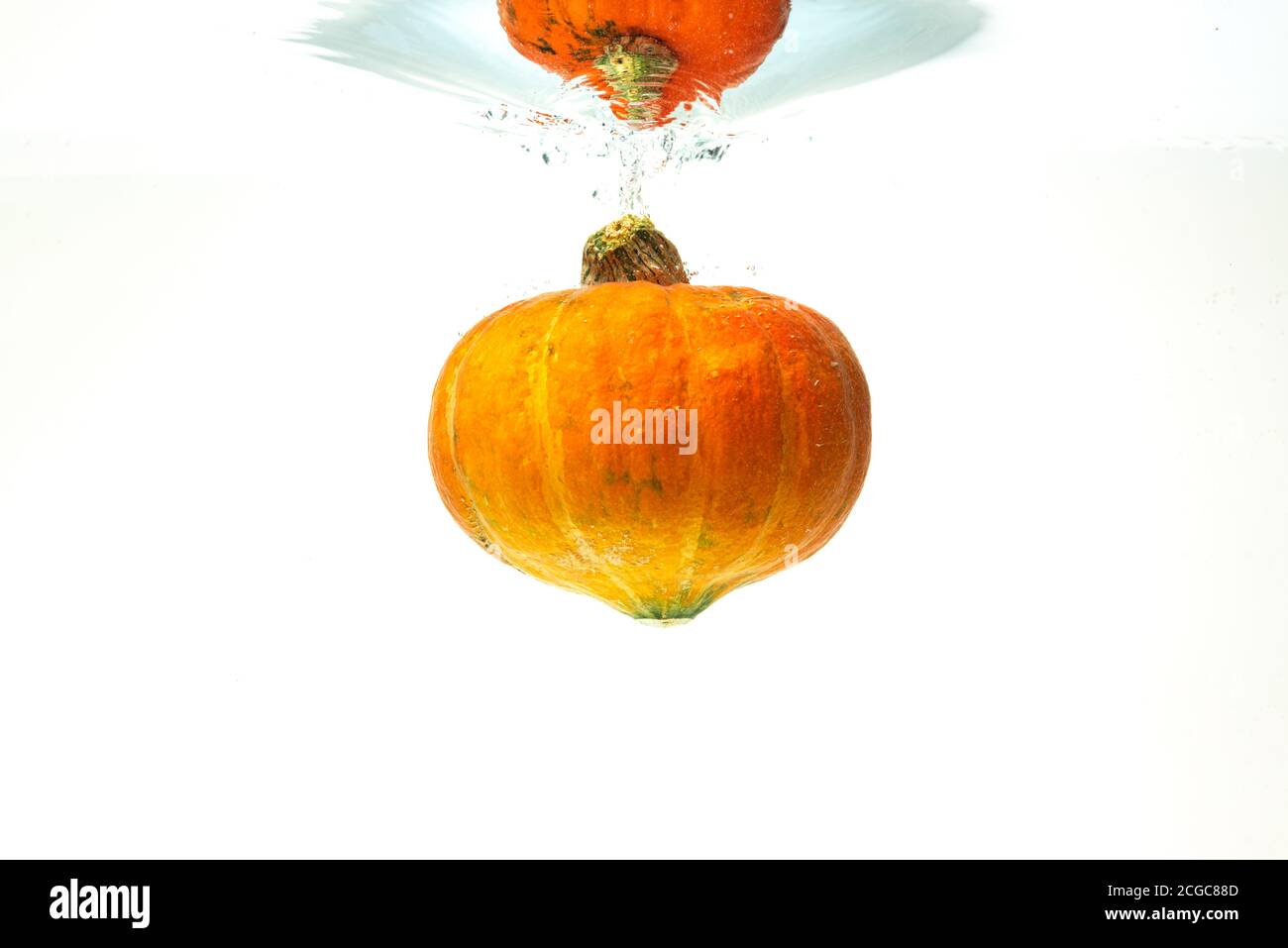 Orange pumpkin splashing into crystal clear water. Product isolated on ...