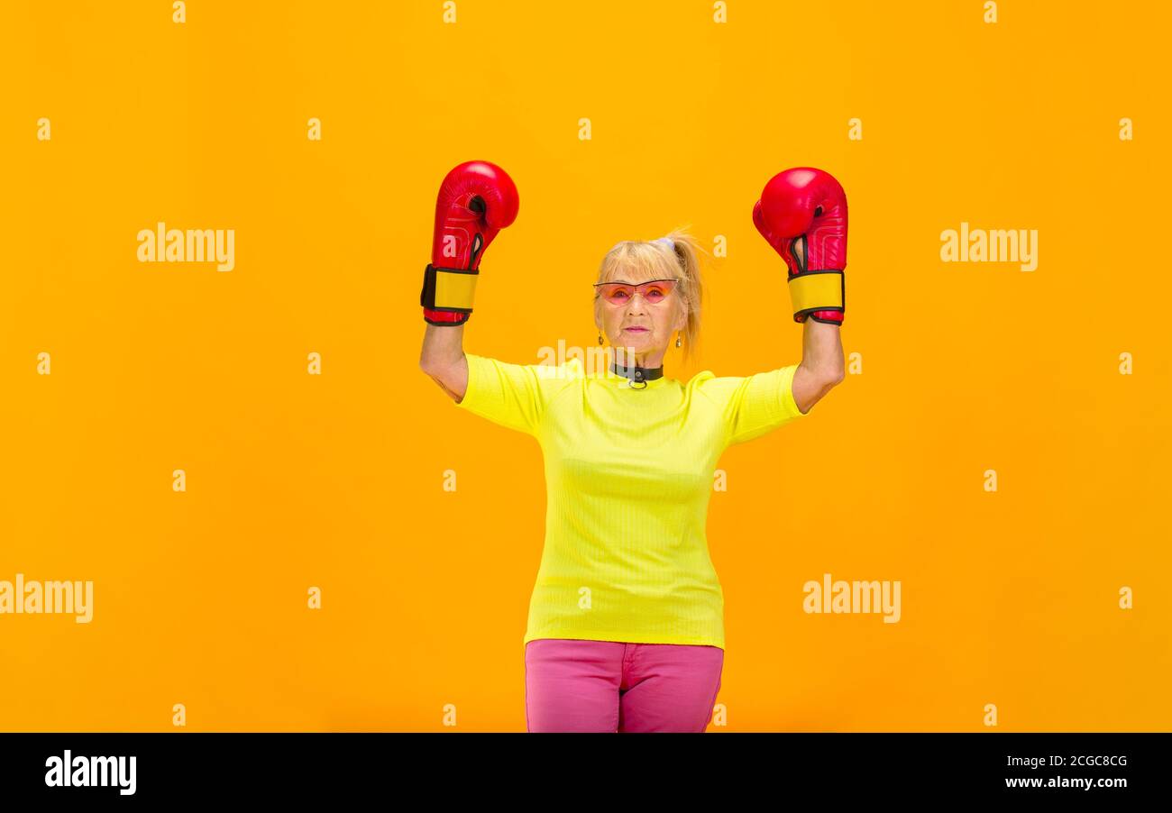 Boxing winner. Senior woman in ultra trendy attire isolated on bright ...