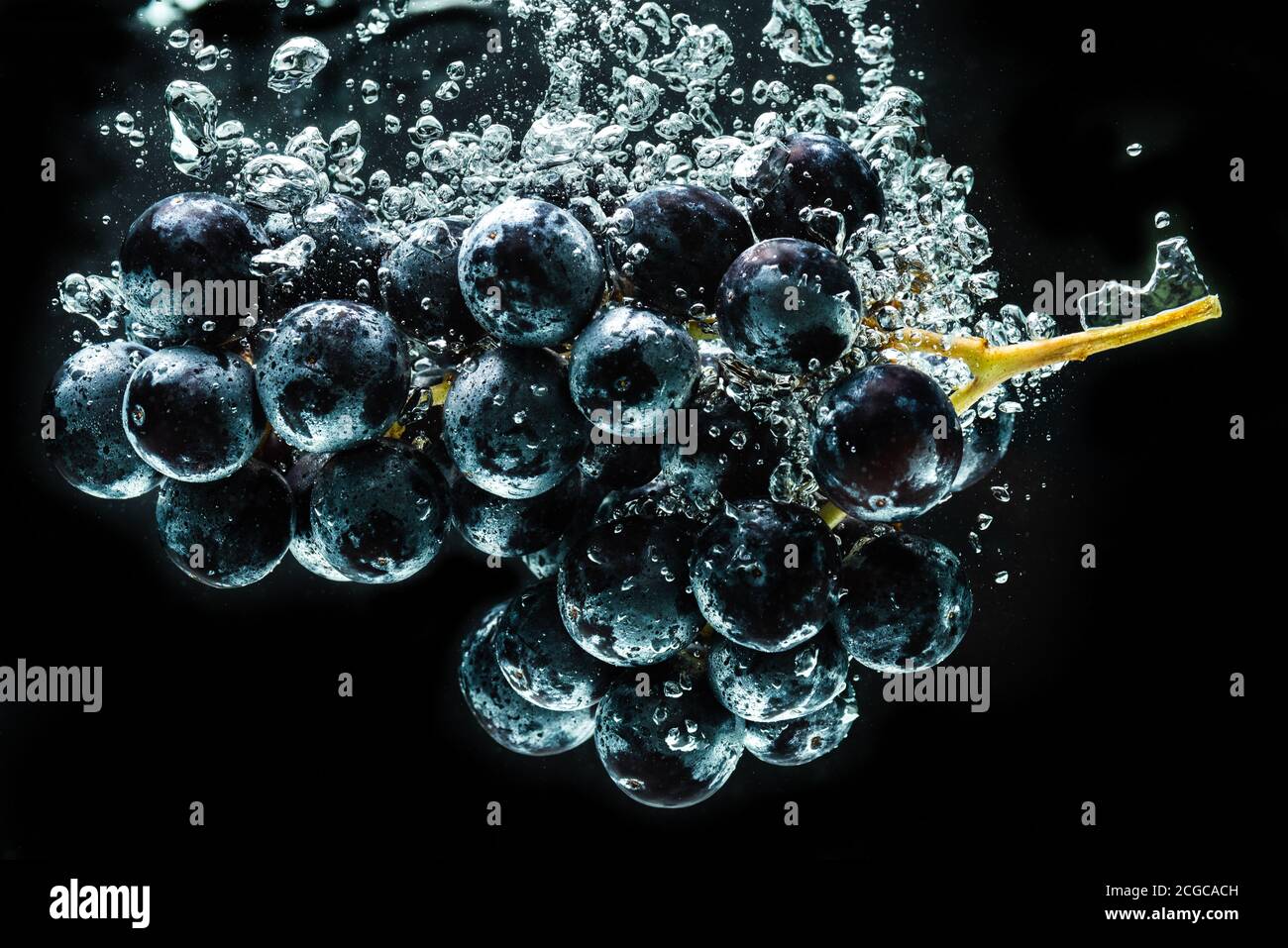 Bunch of red grapes splashing into clear water isolated against black ...