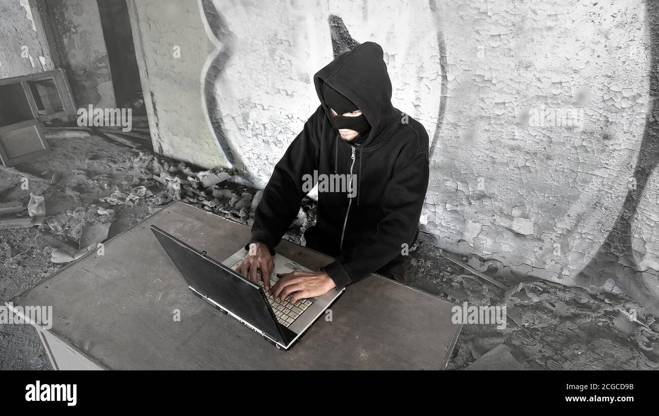 Hacker and laptop meaning safety data. Cyberterrorist in an abandoned ...