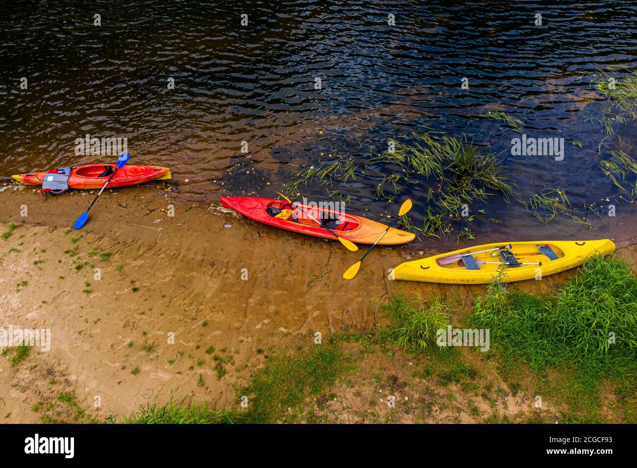 multicolored empty kayaks and canoes on the river bank, top down view ...