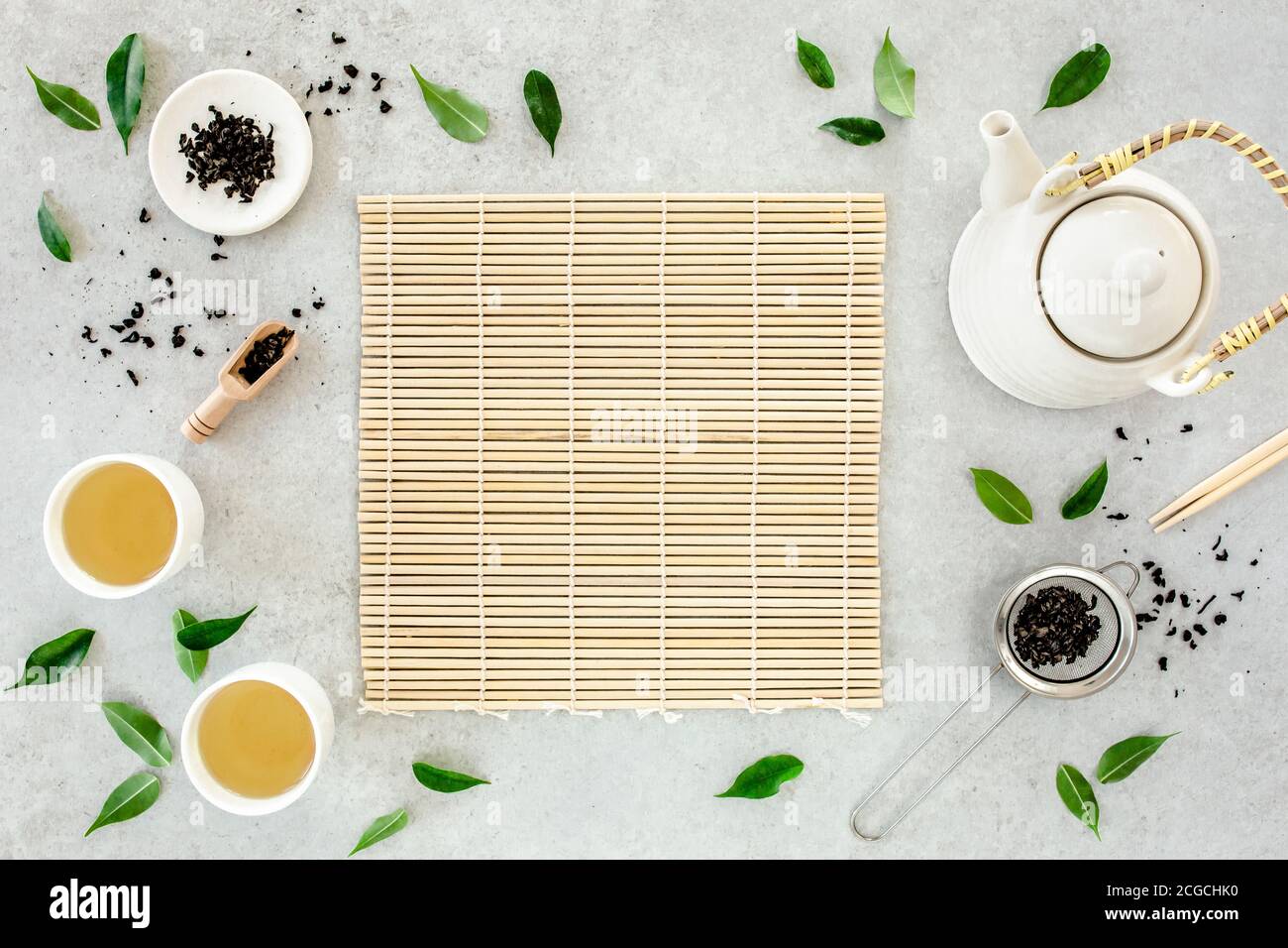 Herbal tea with two white tea cups and teapot, with green tea leaves ...