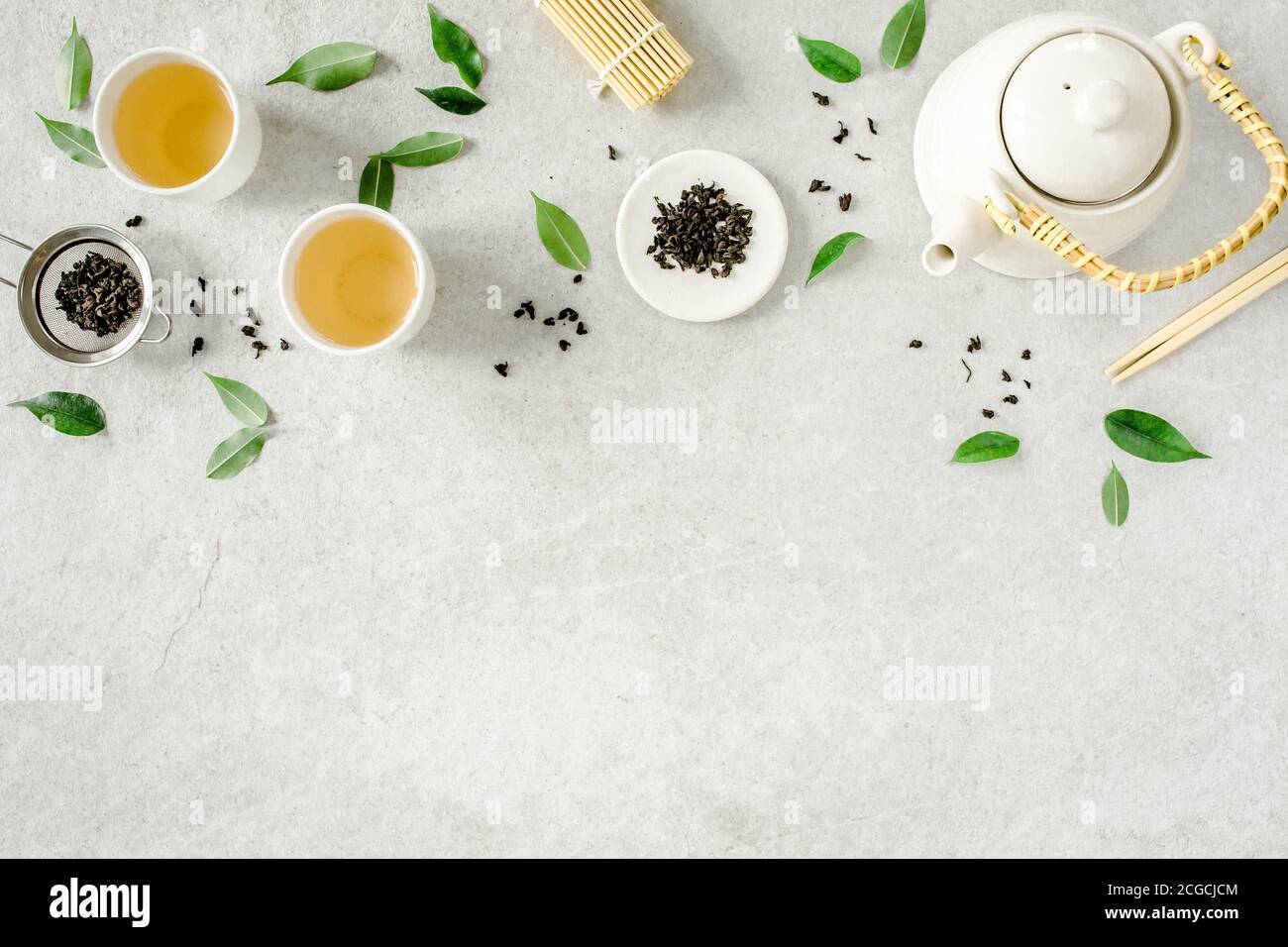 Herbal tea with two white tea cups and teapot, with green tea leaves ...