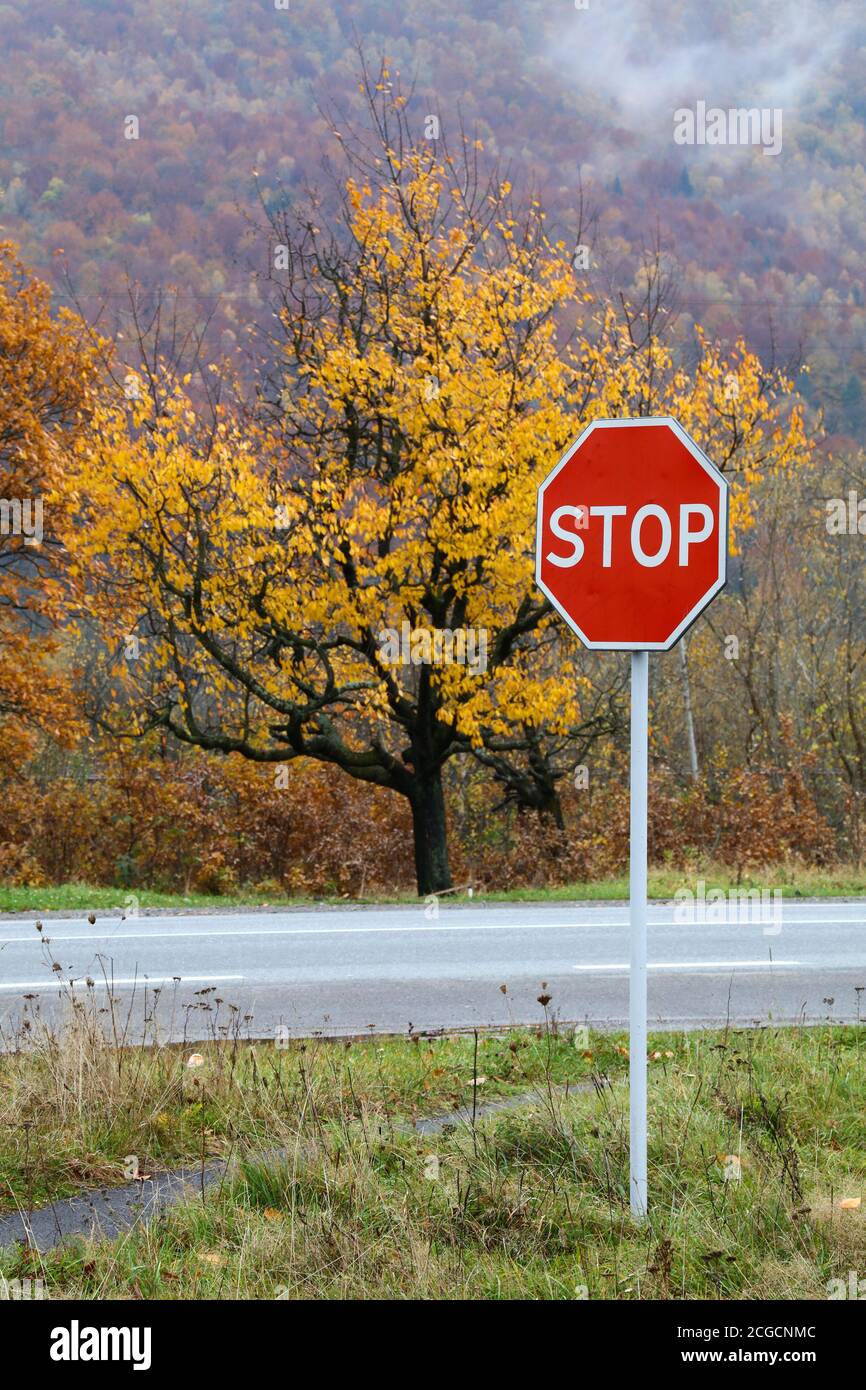 Close up road warning STOP sign over autumn mountain forest landscape ...