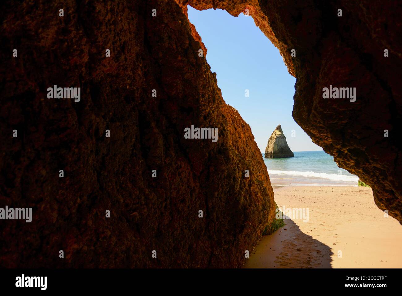 A stunning view from inside a small cave, looking out onto the beach in ...