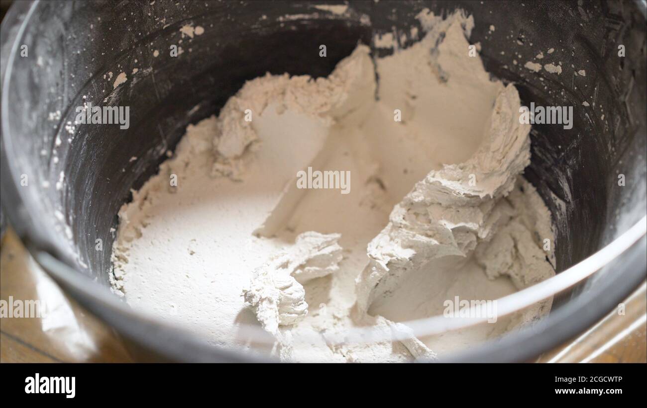 House painter plasterer stirs the putty in a bucket with a handheld ...