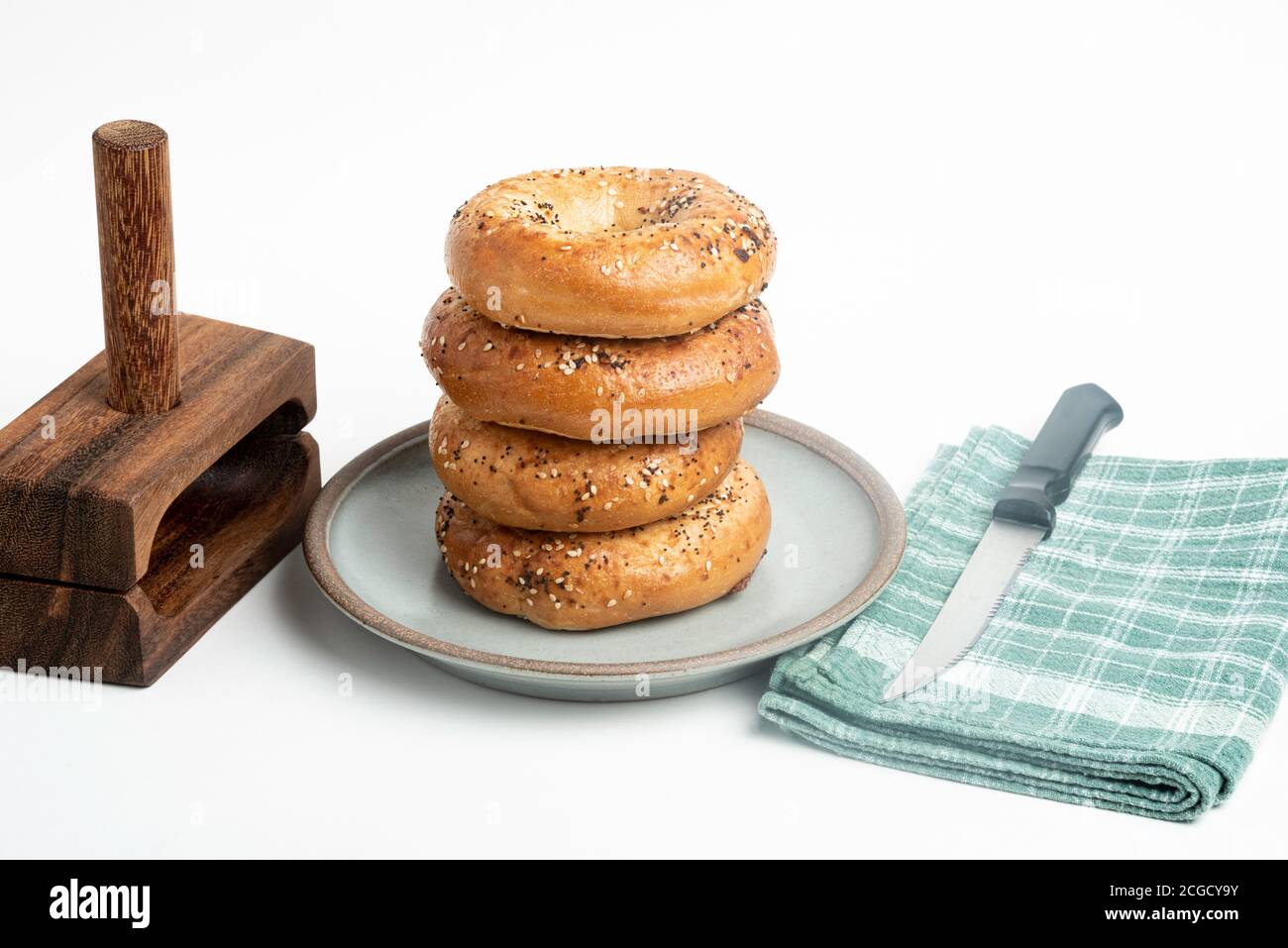 A single tall stack of four freshly baked bagels on a ceramic plate ...