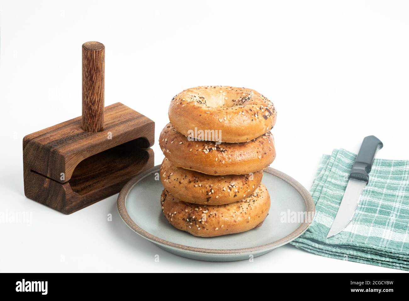 A single tall stack of four freshly baked bagels on a ceramic plate ...
