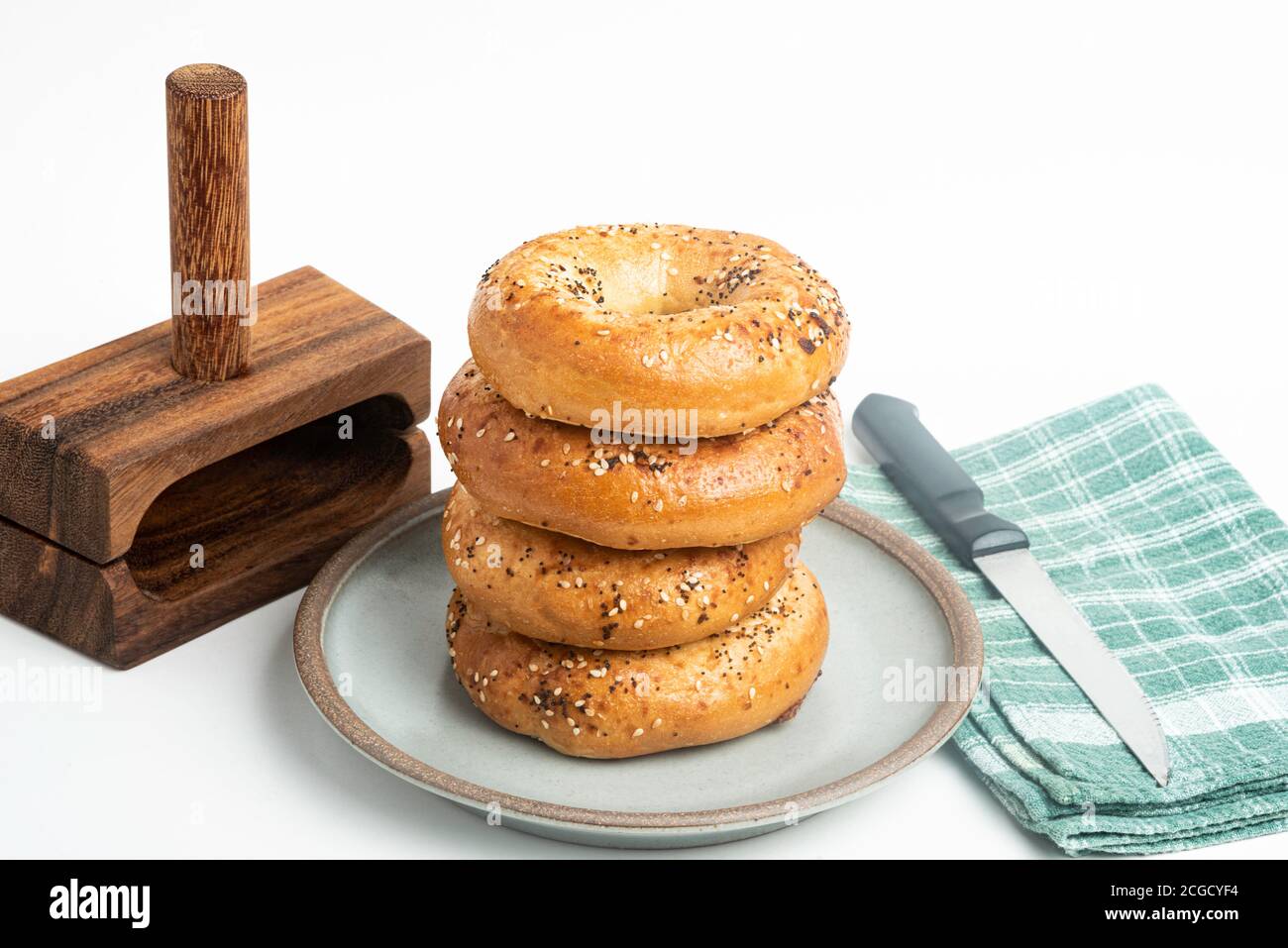 A single tall stack of four freshly baked bagels on a ceramic plate ...