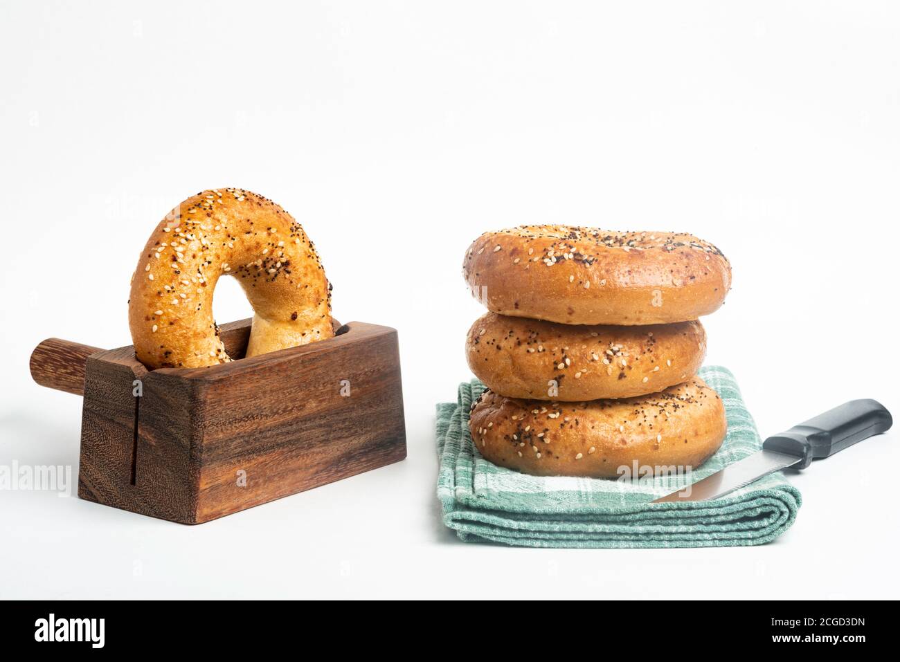 A single tall stack of three freshly baked bagels on a napkin with one ...