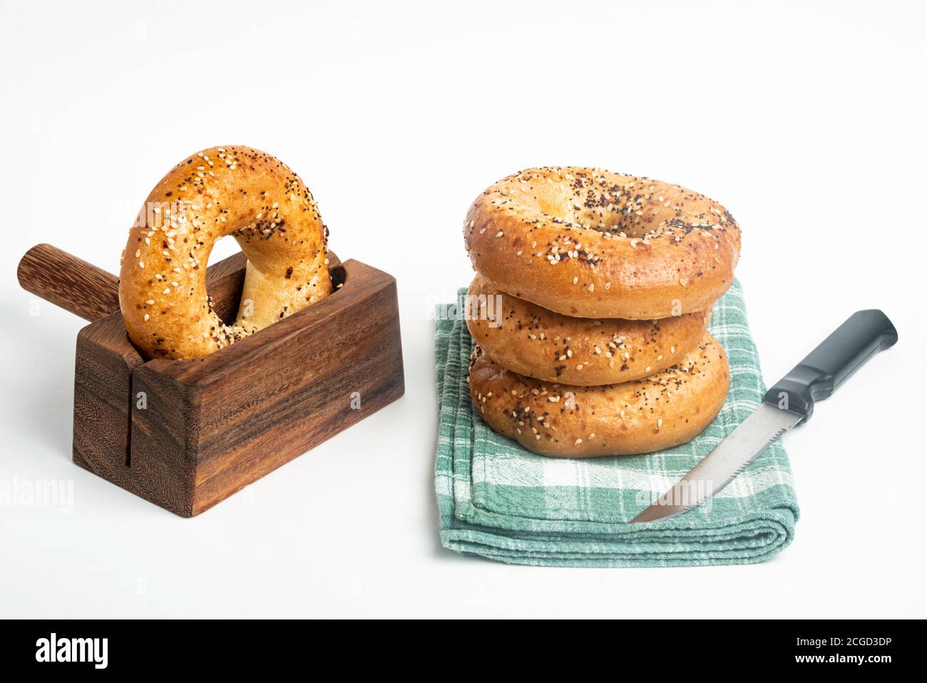 A single tall stack of three freshly baked bagels on a napkin with one ...