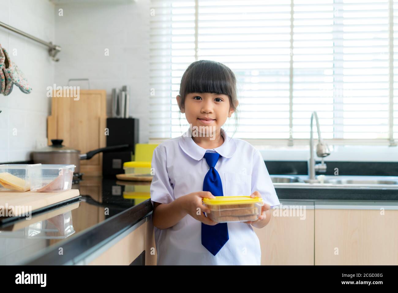Asian elementary school student girl in uniform making sandwich for ...