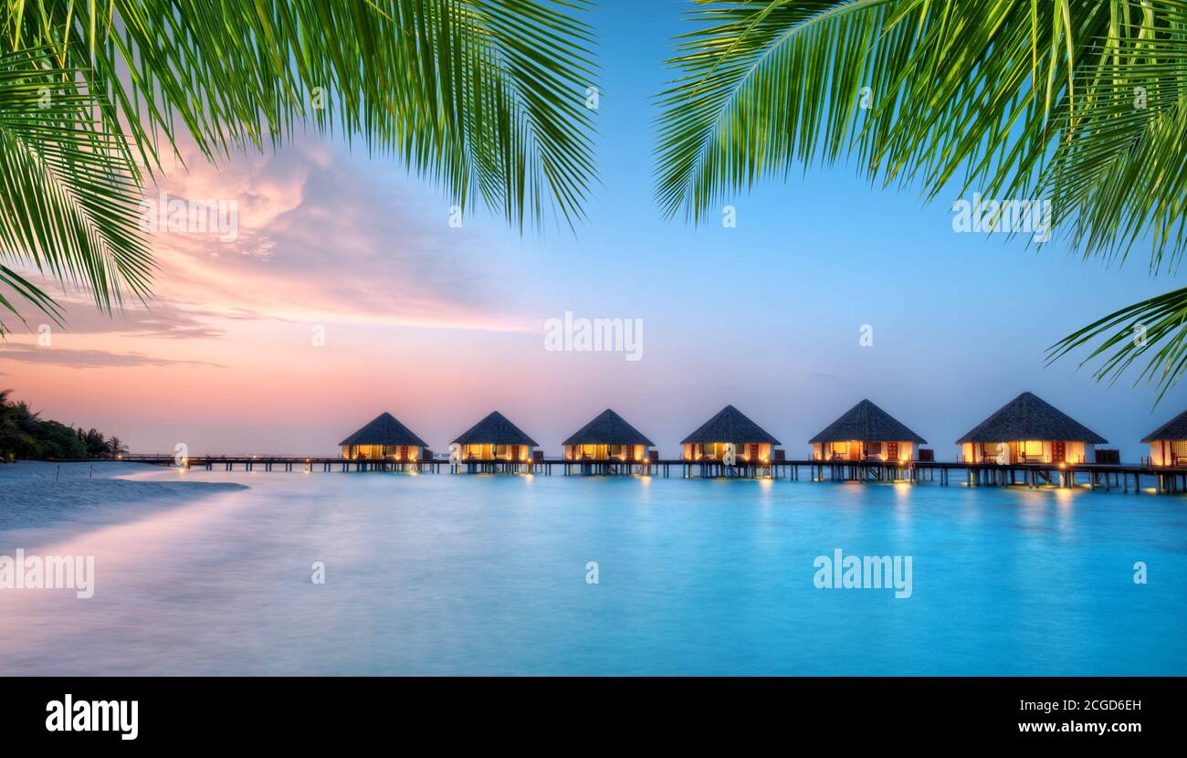 Water villas in lagon, Maldives resort island in sunset. Detail of palm ...