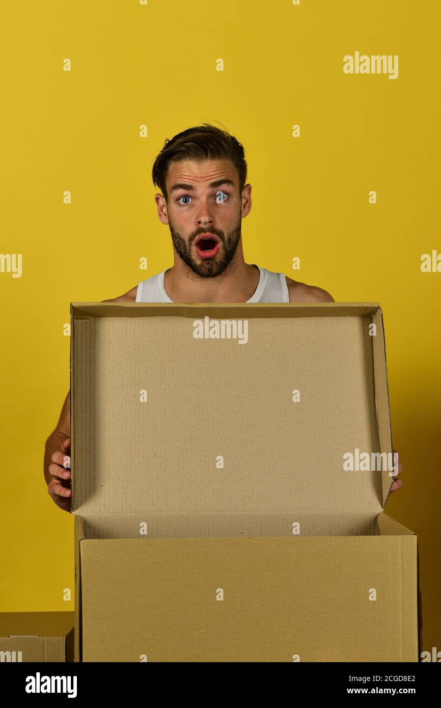 Man holding empty cardboard box. Guy with carton on yellow background ...