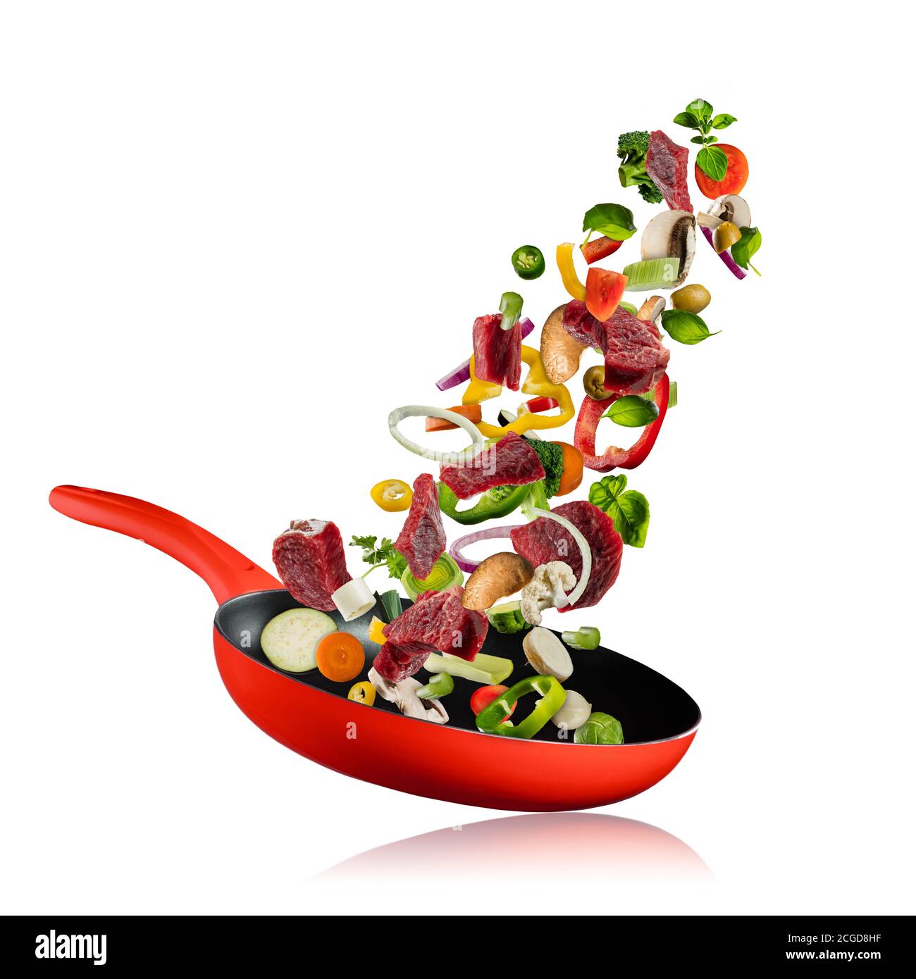 Fresh vegetables and pieces of beef meat flying into a pan, isolated on ...