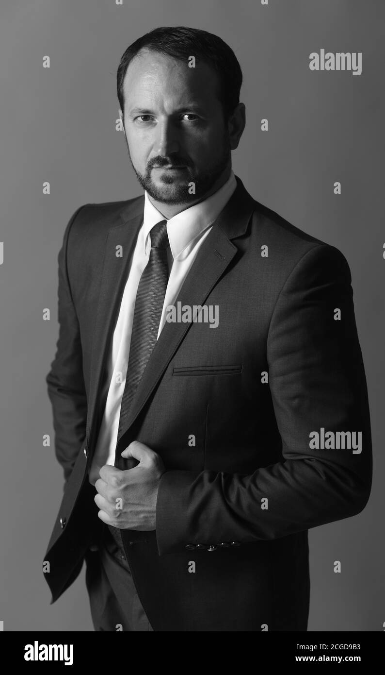 Leader holds hand in pocket on dark grey background, black and white ...