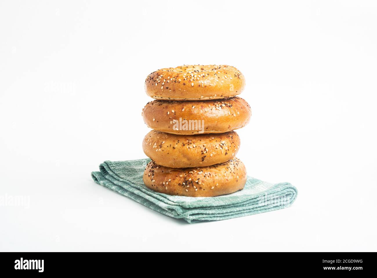 A single tall stack of four freshly baked bagels on a green napkin set ...