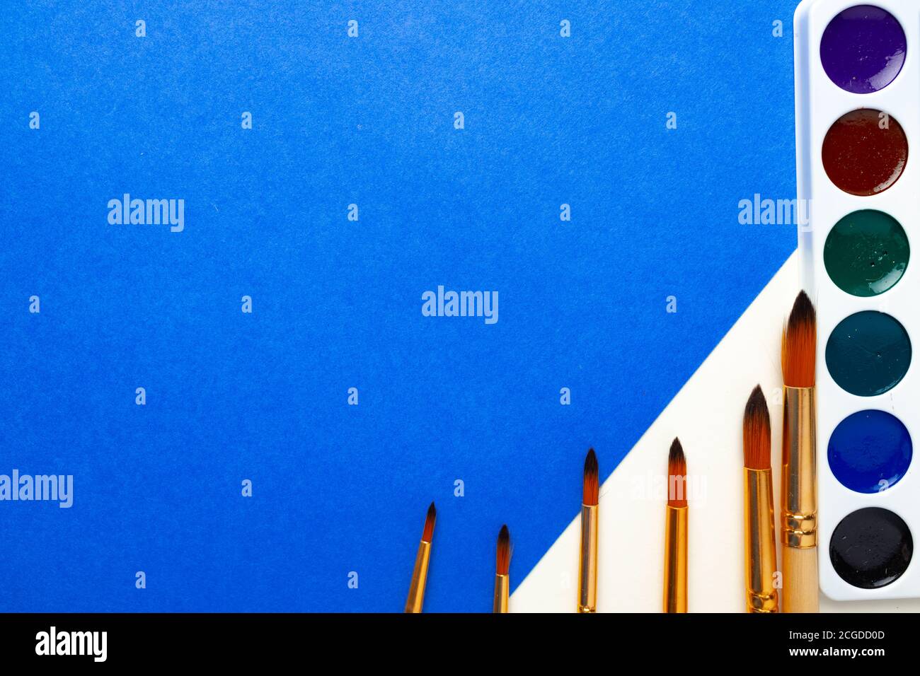 Watercolor paint box and set of brushes on blue and white background ...