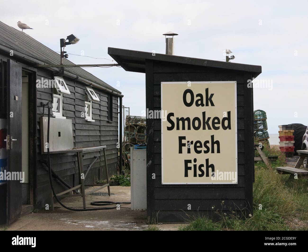 Signage on the end of a black beach hut advertises oak smoked fresh ...