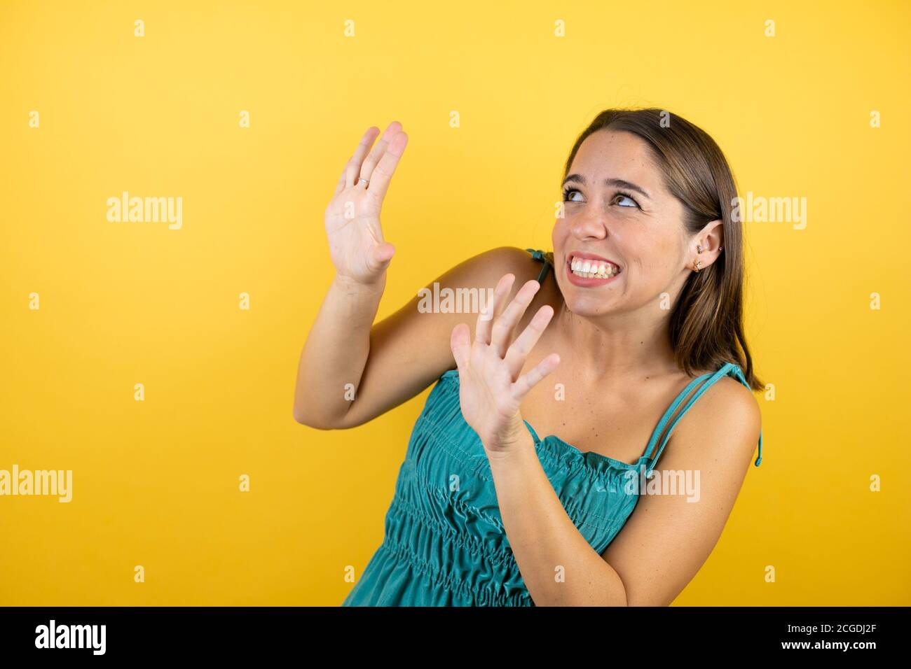 Young beautiful woman over isolated yellow background scared with her ...